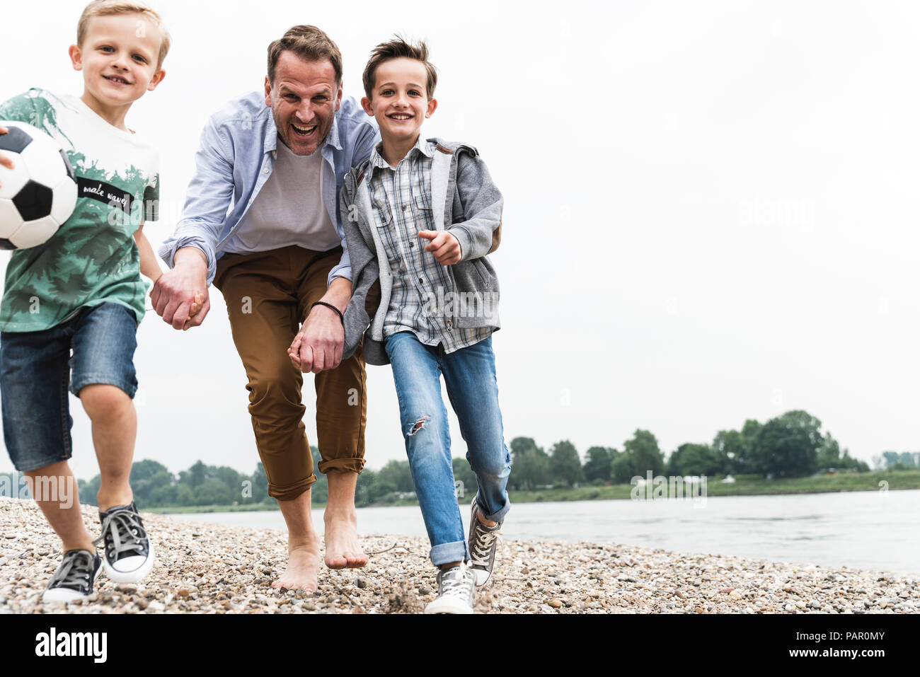 Happy father with two sons and football at the riverside Stock Photo ...