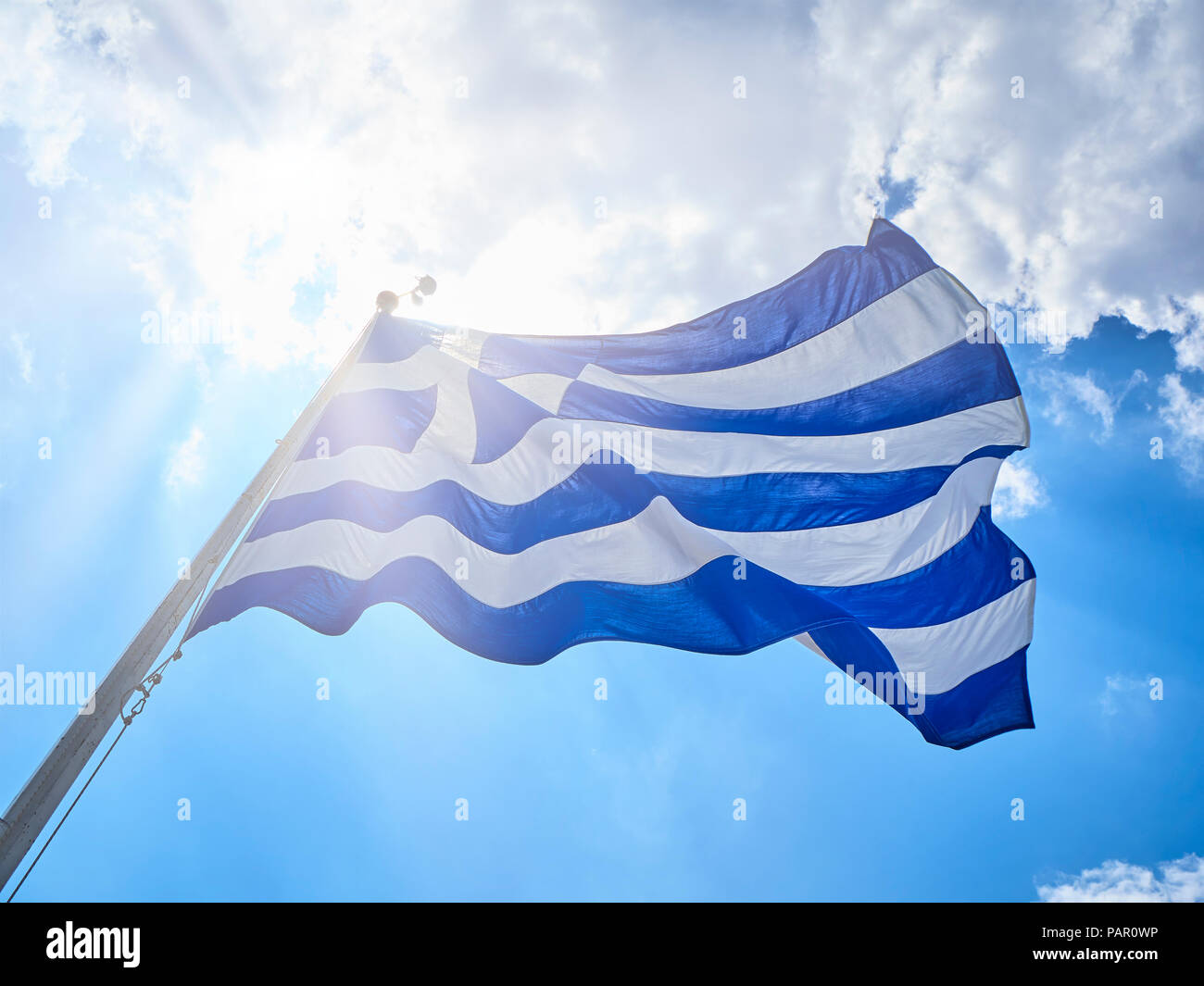 Official flag of Greece waving on a cloudy sky and sunlight rays Stock ...