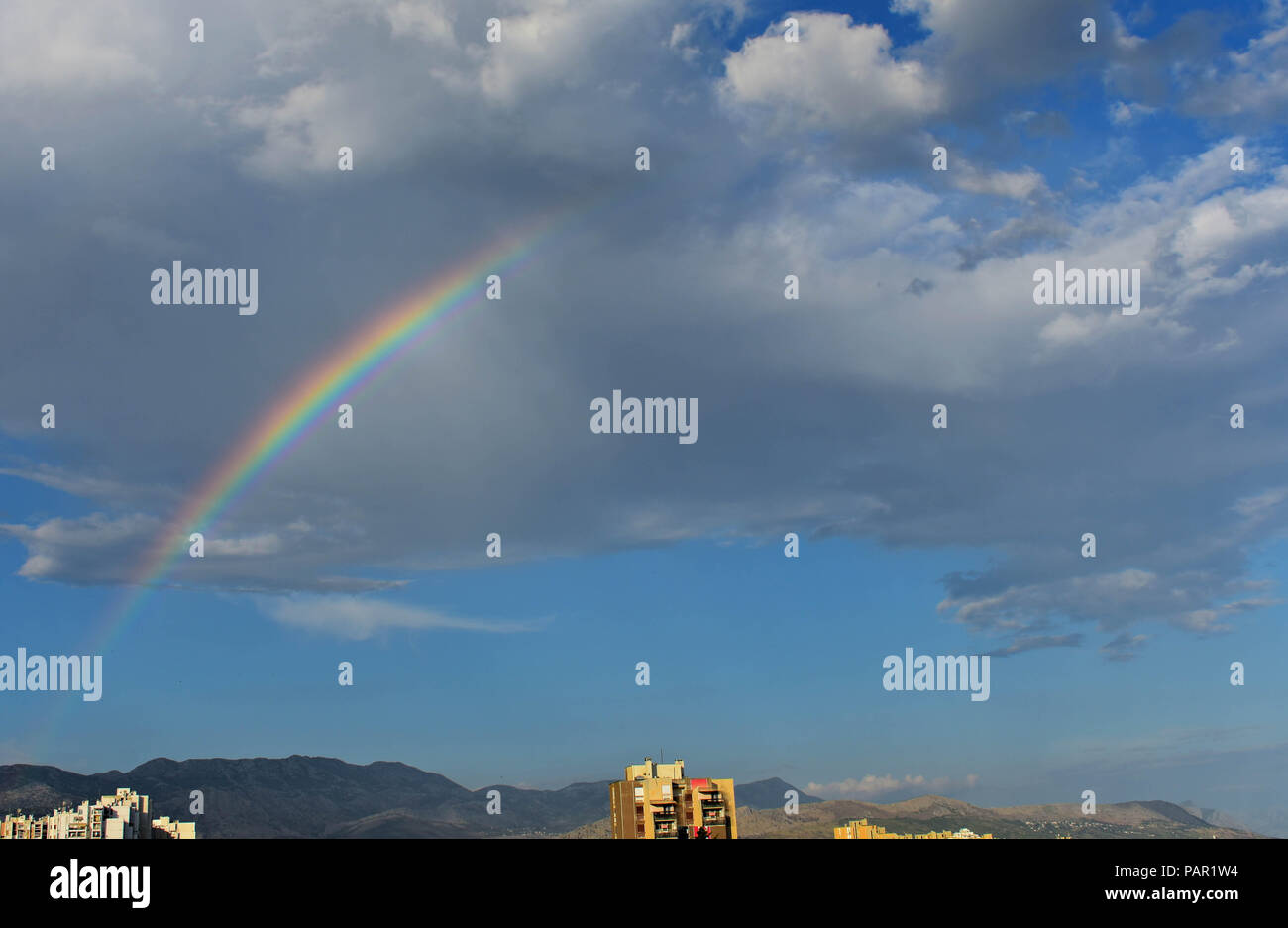 Bright colorful rainbow over city, sun shining in rainy day, beautiful ...