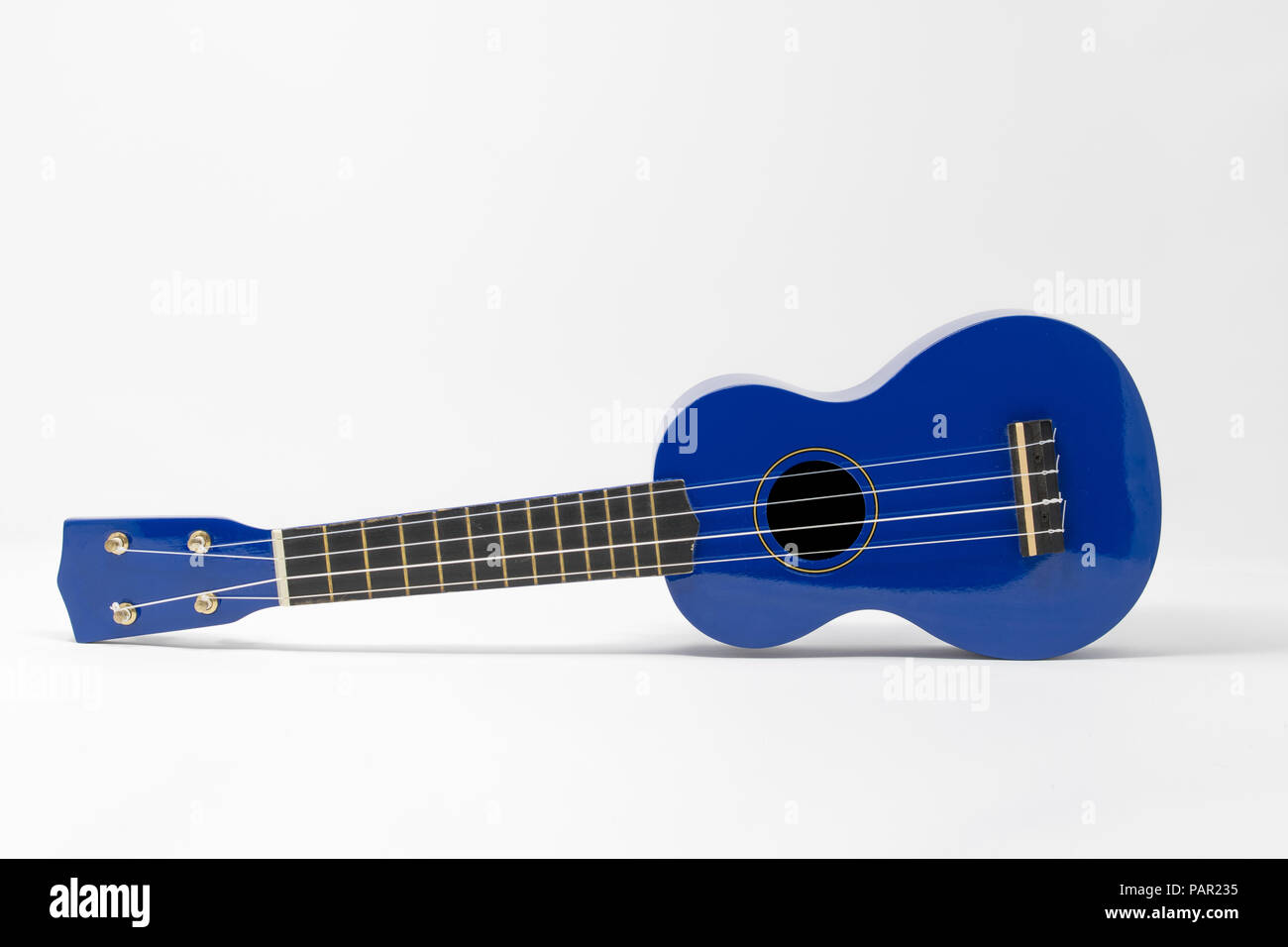 A blue ukulele set against a white background Stock Photo - Alamy