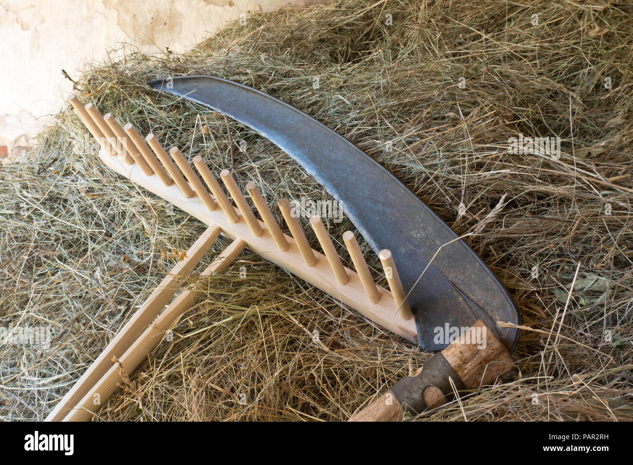 A scythe and a rake with hay Stock Photo - Alamy