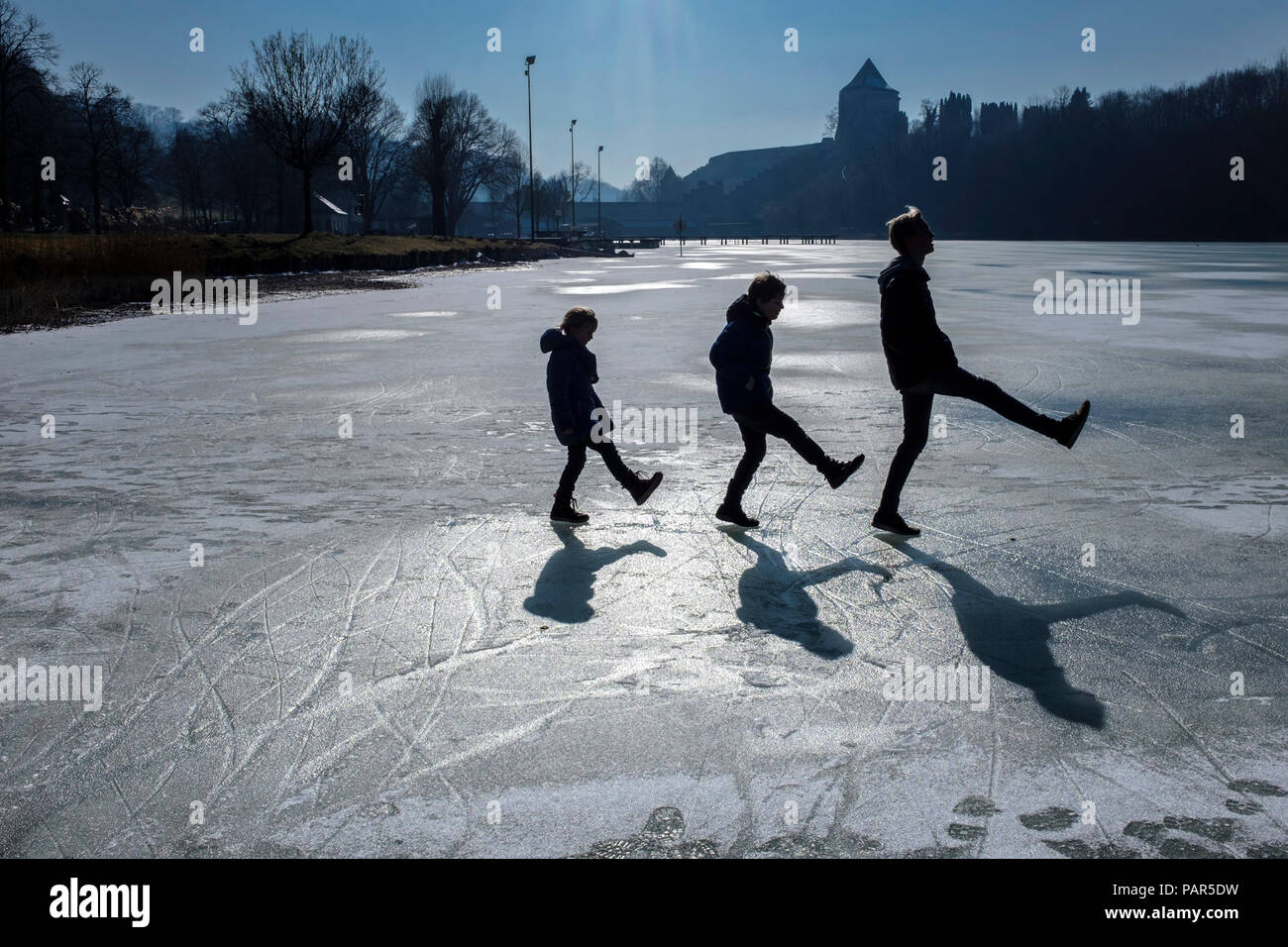 Three children playing on icy surface Stock Photo - Alamy