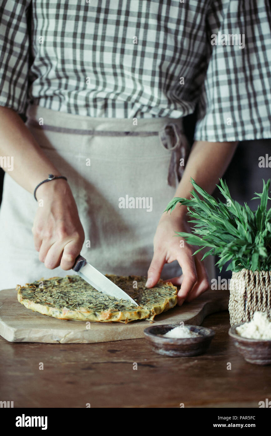 Young woman slicing homemade chickpea and herb cake Stock Photo - Alamy