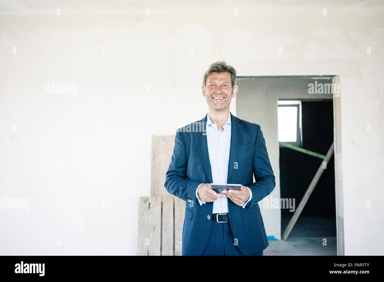 Portrait of smiling man in suit in building under construction Stock ...