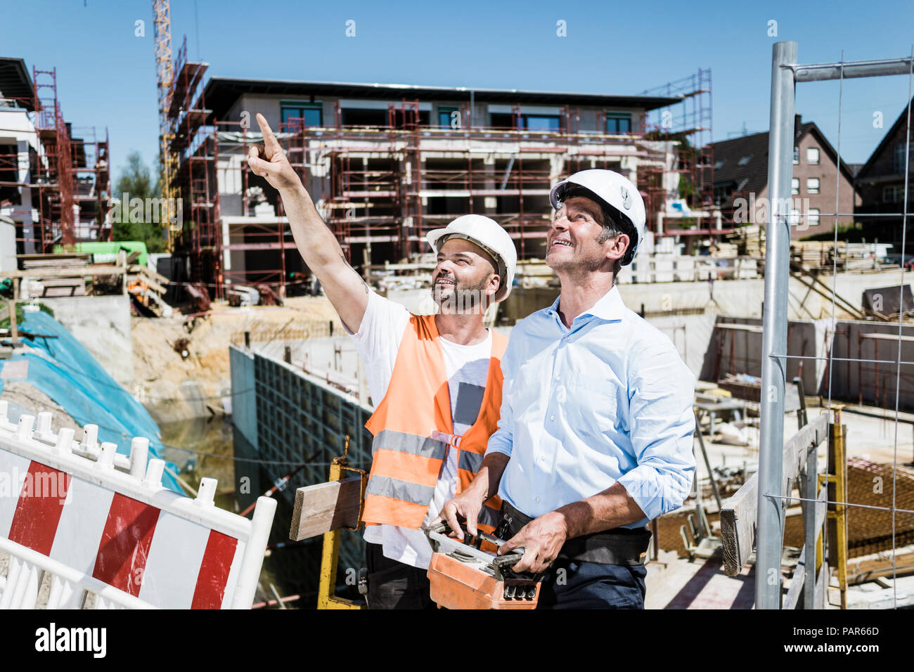 Smiling construction worker talking to man on construction site Stock ...