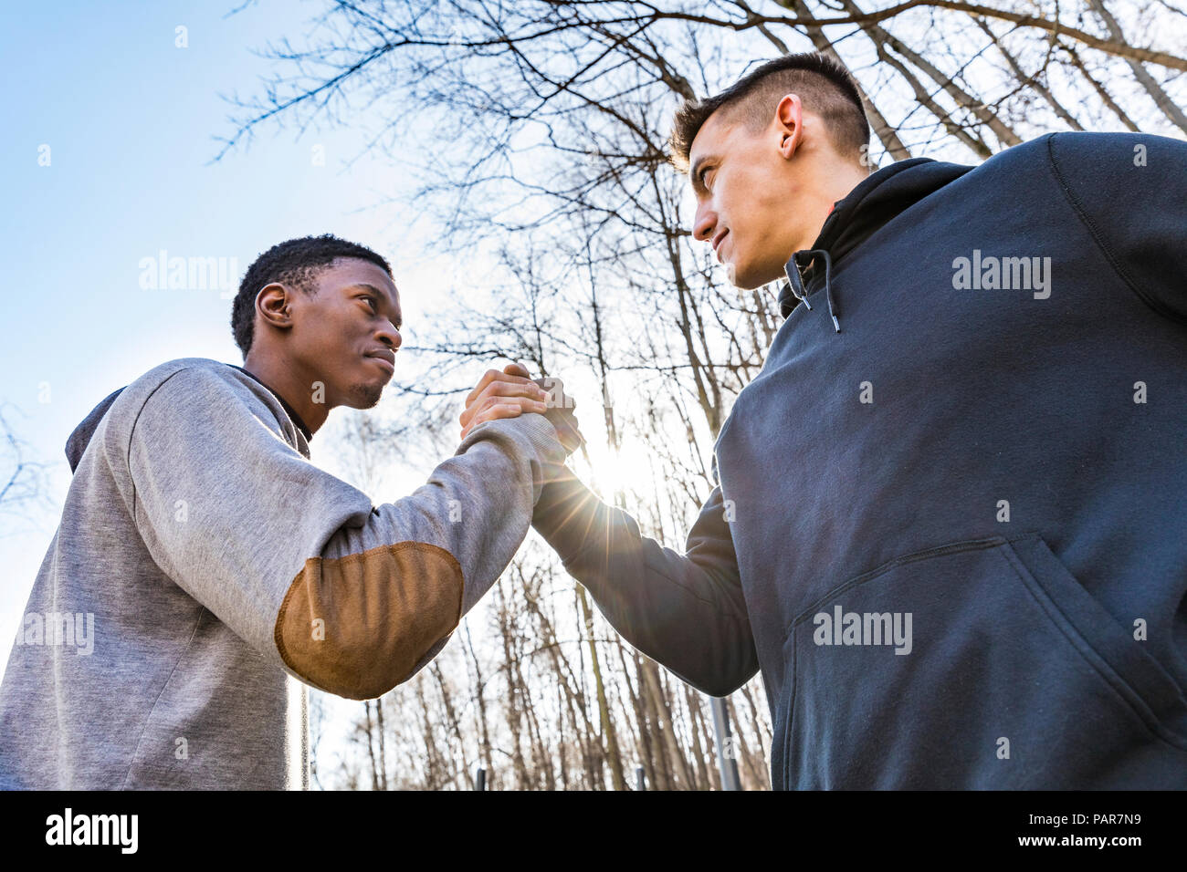Two sportive young men shaking hands outdoors Stock Photo - Alamy