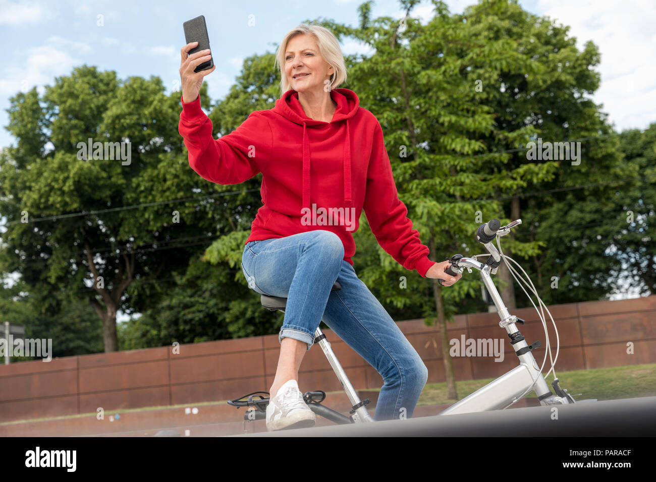 Senior woman with city bike using cell phone Stock Photo - Alamy