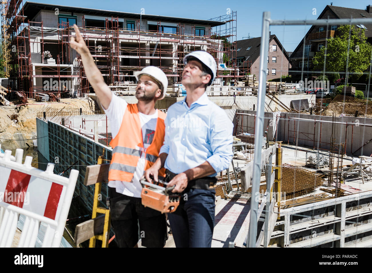Construction worker talking to man on construction site Stock Photo - Alamy