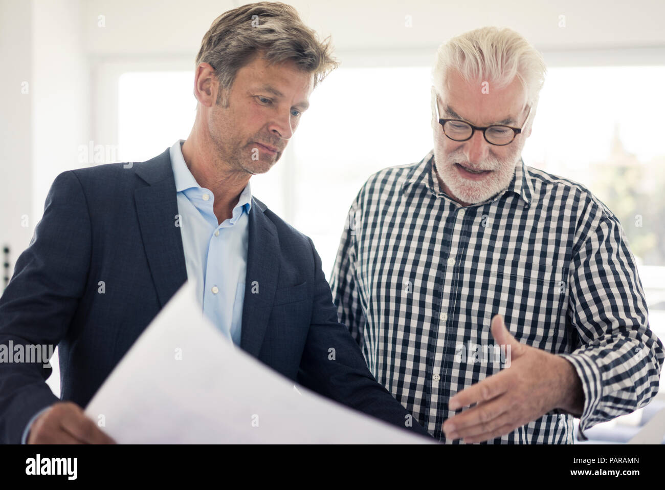 Man in suit and senior man looking at blueprint Stock Photo - Alamy
