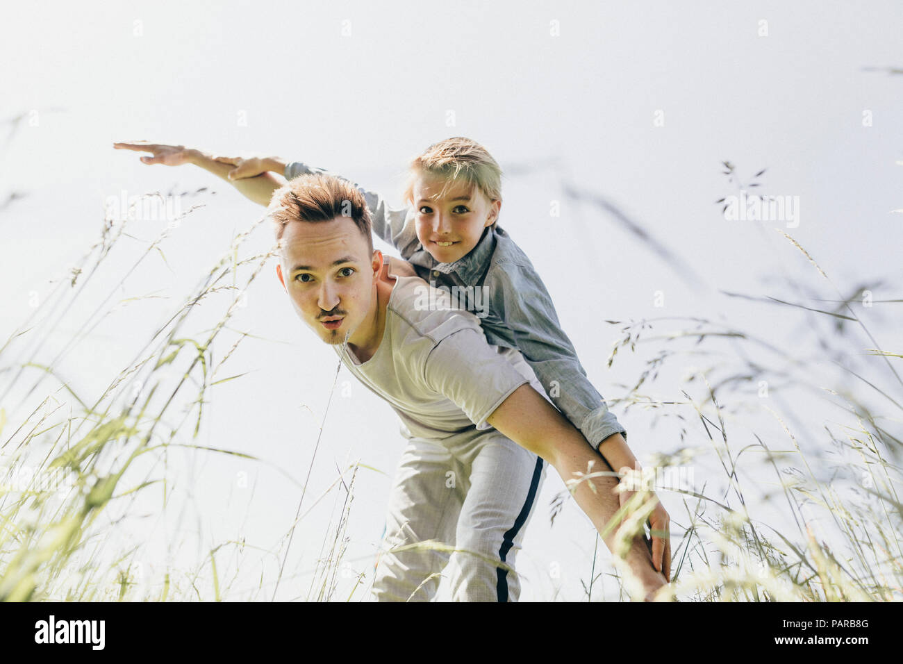 Young man and boy in a field pretending to fly Stock Photo - Alamy