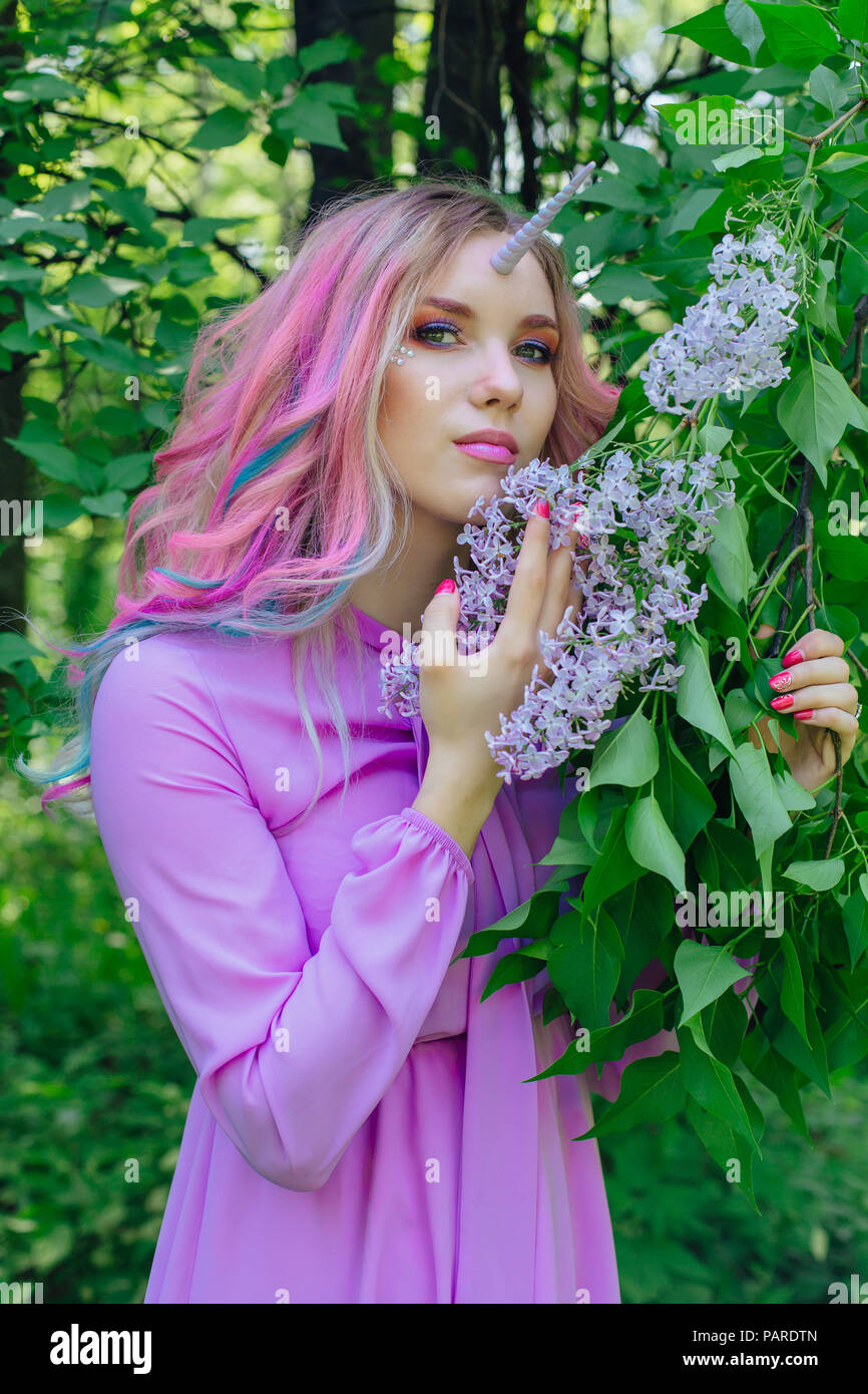 Fairy girl unicorn with rainbow hair and shiny makeup holding lilac ...