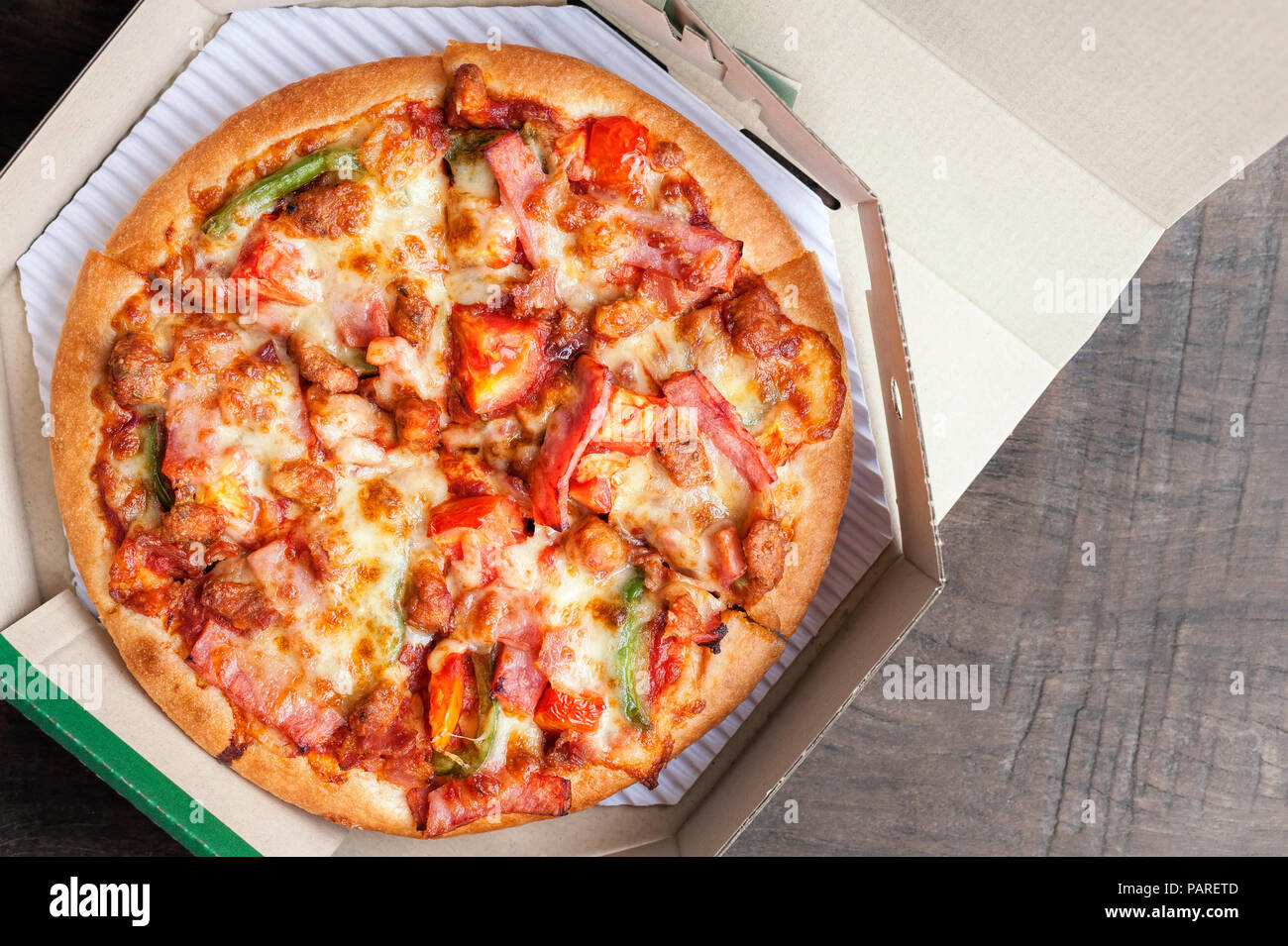 Delicious Italian pizza sliced with bacon, cheese, tomato, capsicum on ...