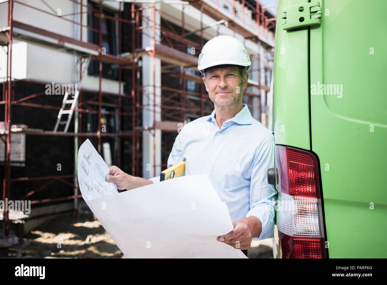 Portrait of architect with blueprint wearing hard hat on construction ...