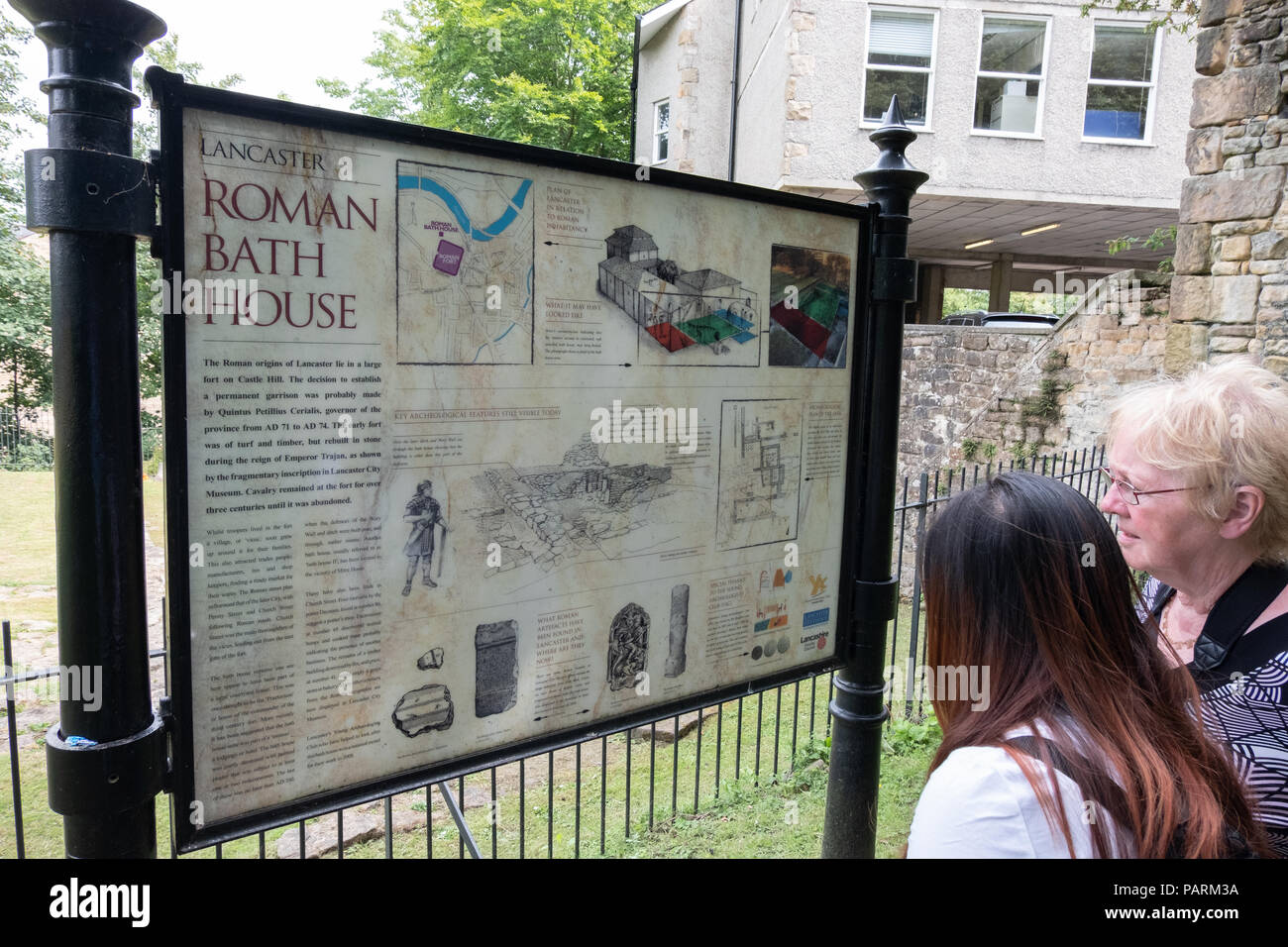 Two ladies looking at the Roman Bath House information board with the ...