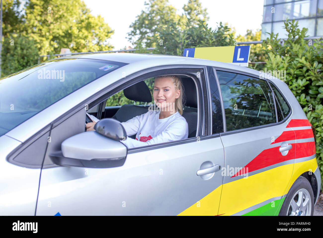 Young happy woman - student sitting in a car driving school. Free space ...