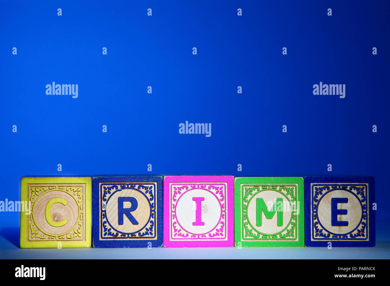 Wooden letter blocks on a blue background spelling out the word crime ...