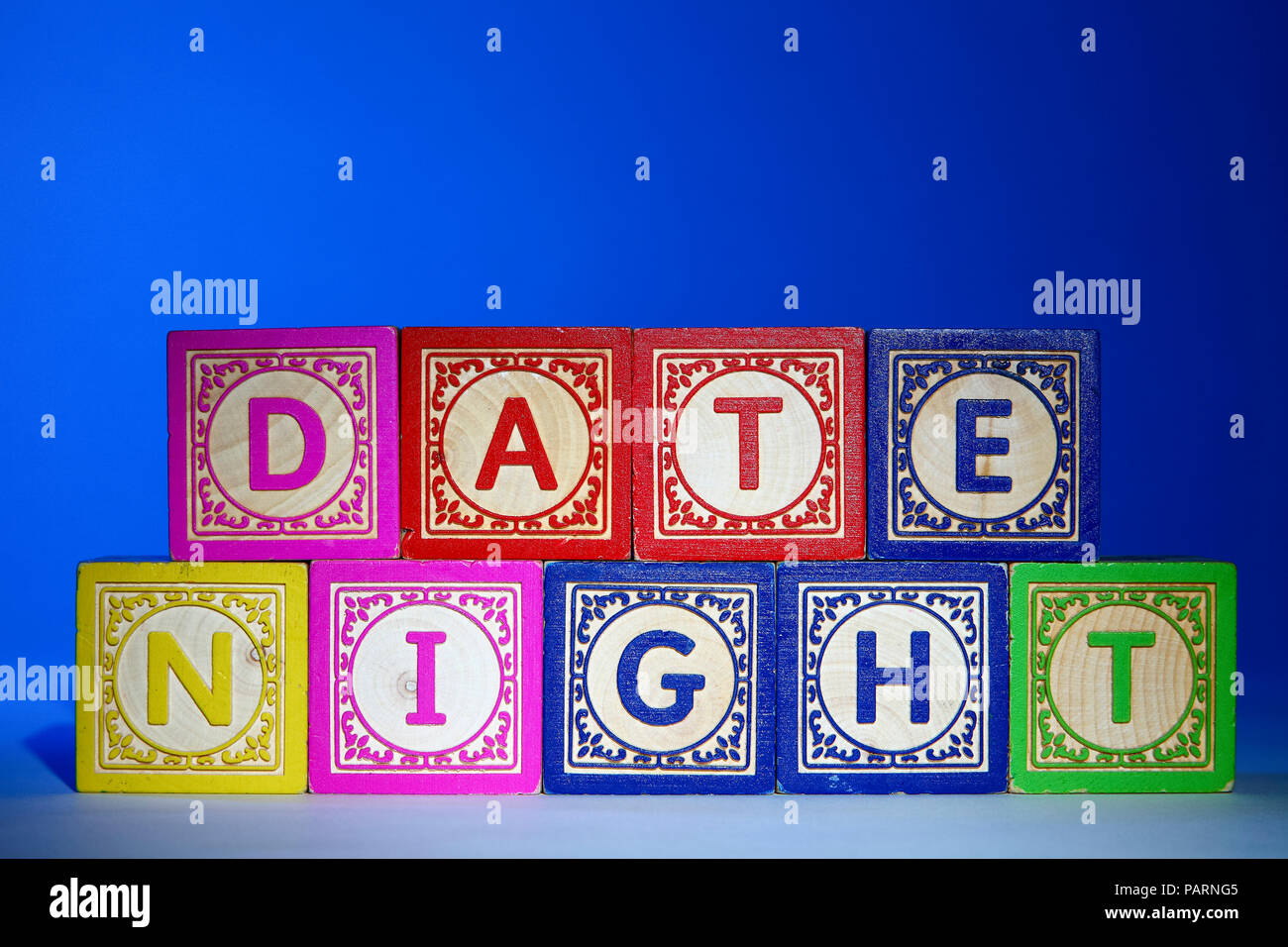 Wooden letter blocks on a blue background spelling out the words date ...