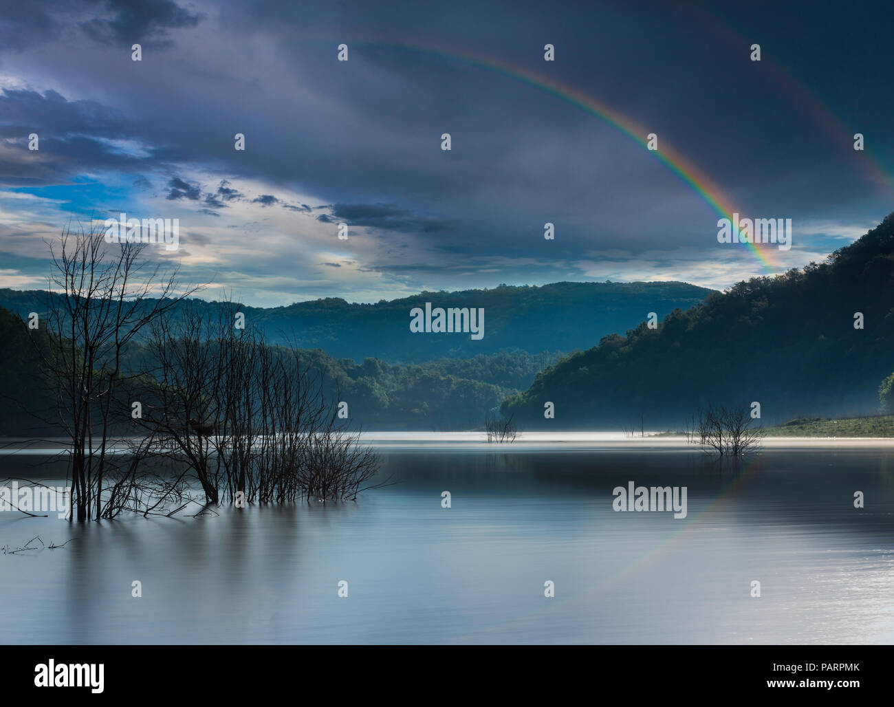 Rainbow reflection in calm lake Stock Photo - Alamy