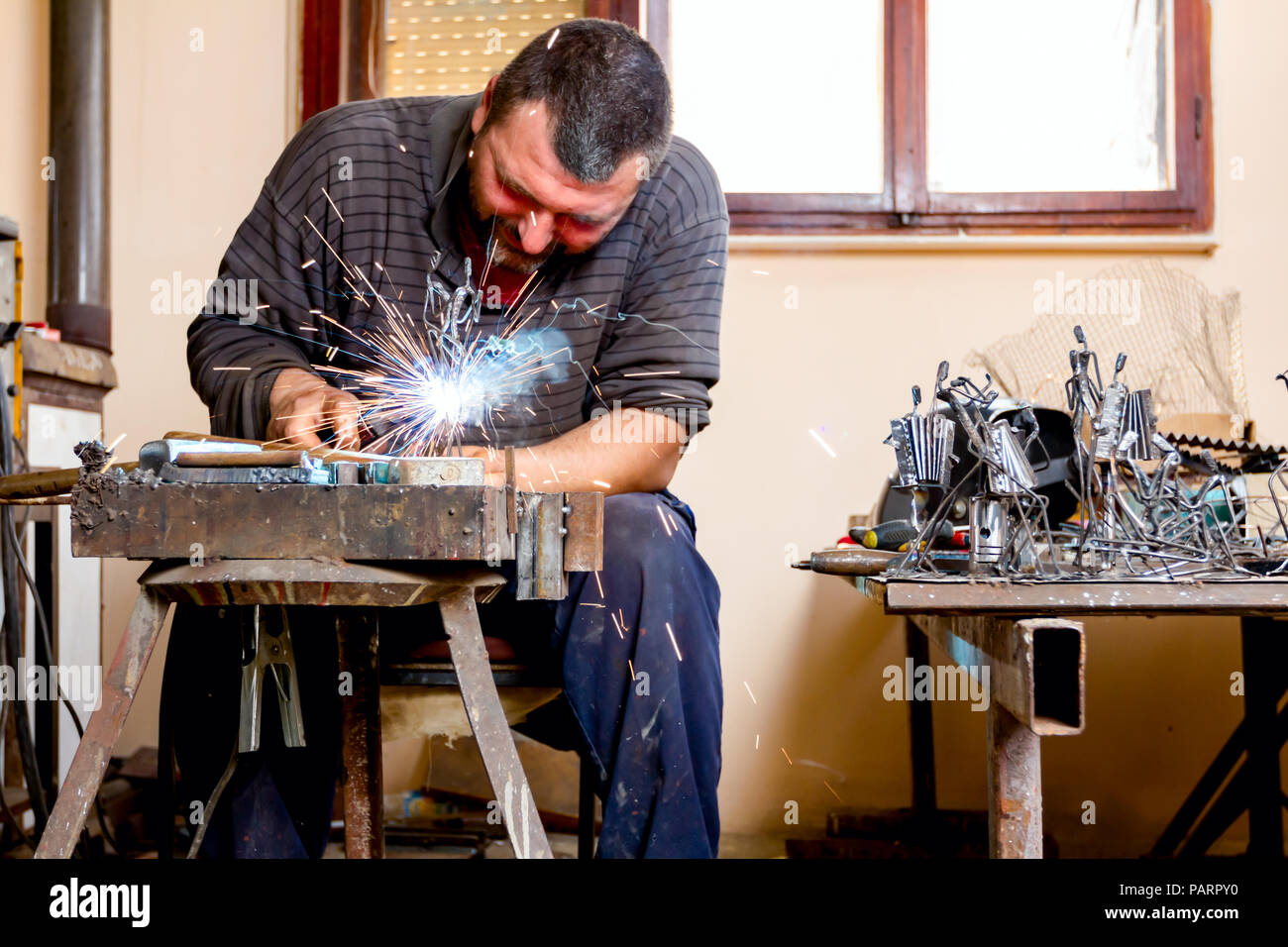 Sculptor is using arc welding to assembly metal sculpture without ...