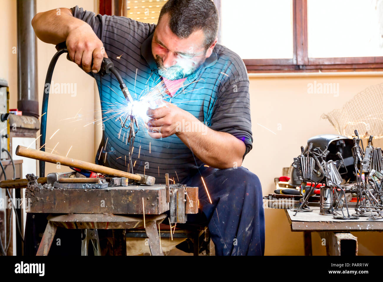 Sculptor is using arc welding to assembly metal sculpture without ...