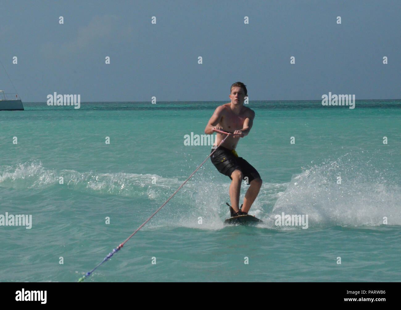 Young guy wakeboarding in a crouch on the waters off Aruba Stock Photo ...
