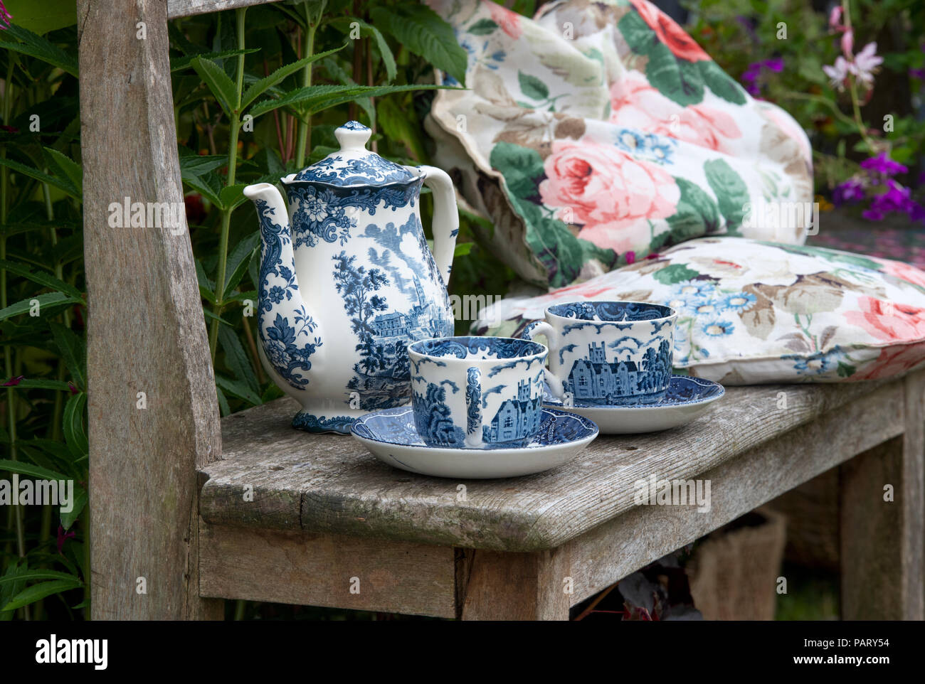 Tea pot and cups on a wooden bench in a show garden at a flower show ...