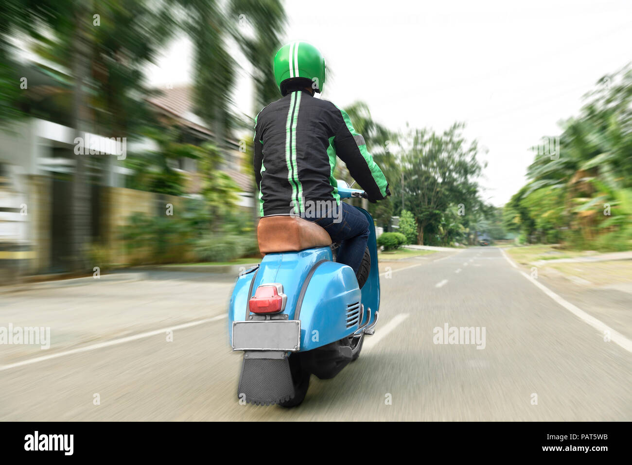 Back view of motorcycle taxi driver with blue scooter on urban street ...