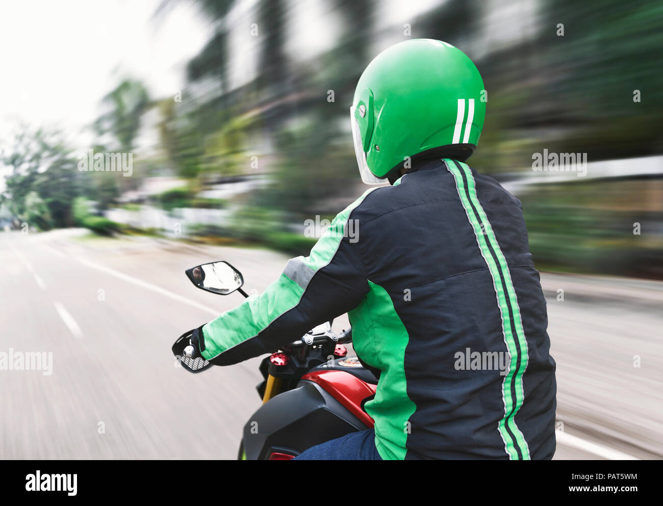 Rear view of motorcycle taxi driver with black and green unifrom on the ...