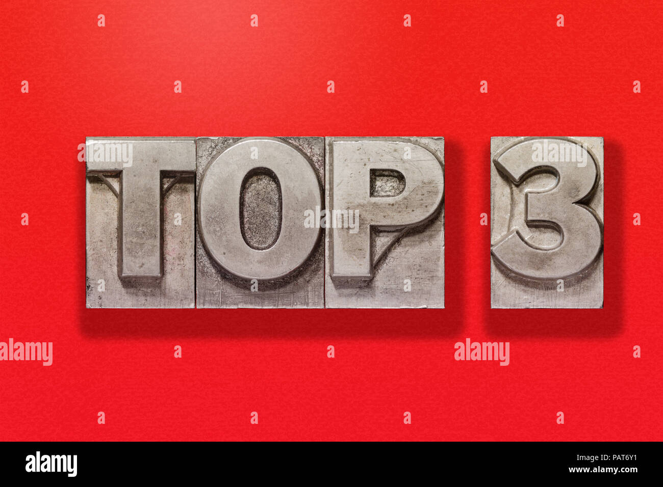 top three metallic letterpress numbers assembled on red textured ...