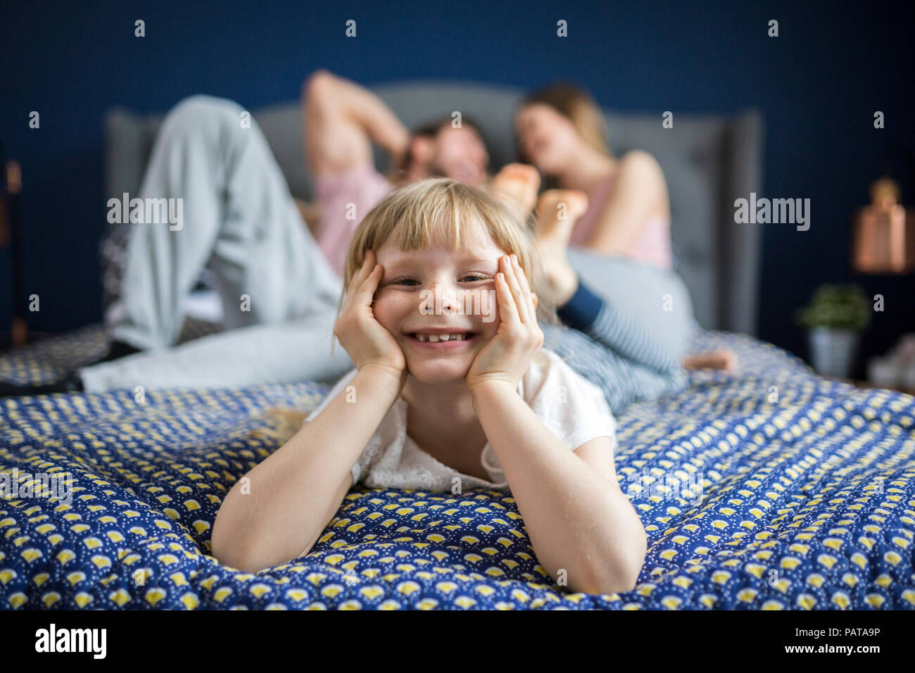 Cheeky little girl lying on bed with her parents Stock Photo - Alamy