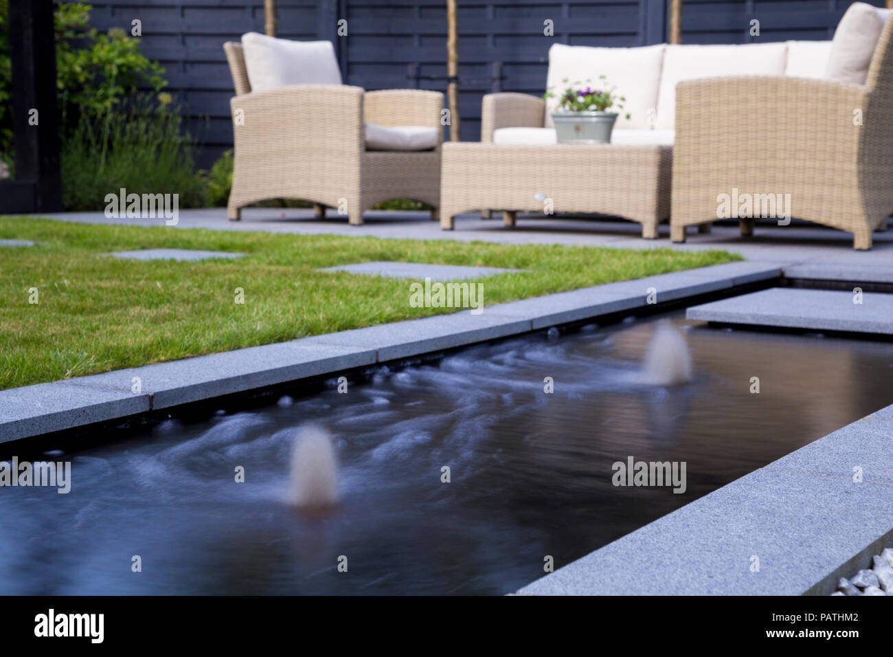 A pool water feature in motion, with view to patio seating area Stock ...