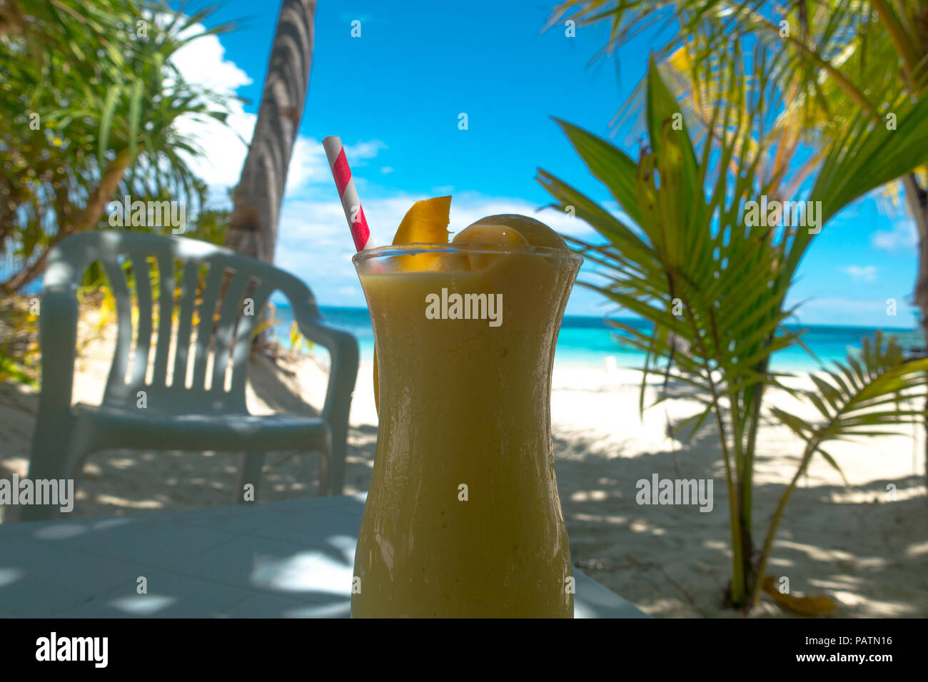 Yellow mango Shake Cocktail with straw, on a sunny paradise beach ...