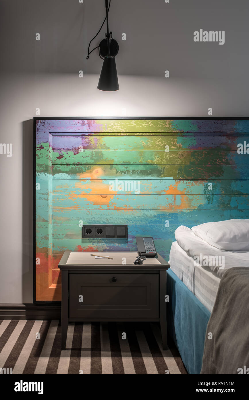 Room in a hotel with a light wall and a striped floor. There is a blue ...