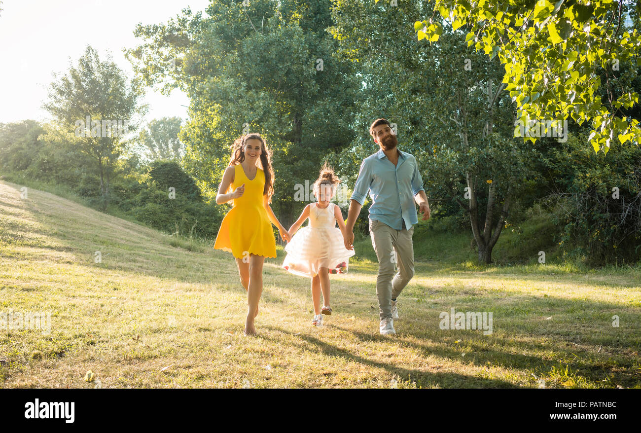 Two happy parents running together with their cute daughter Stock Photo ...