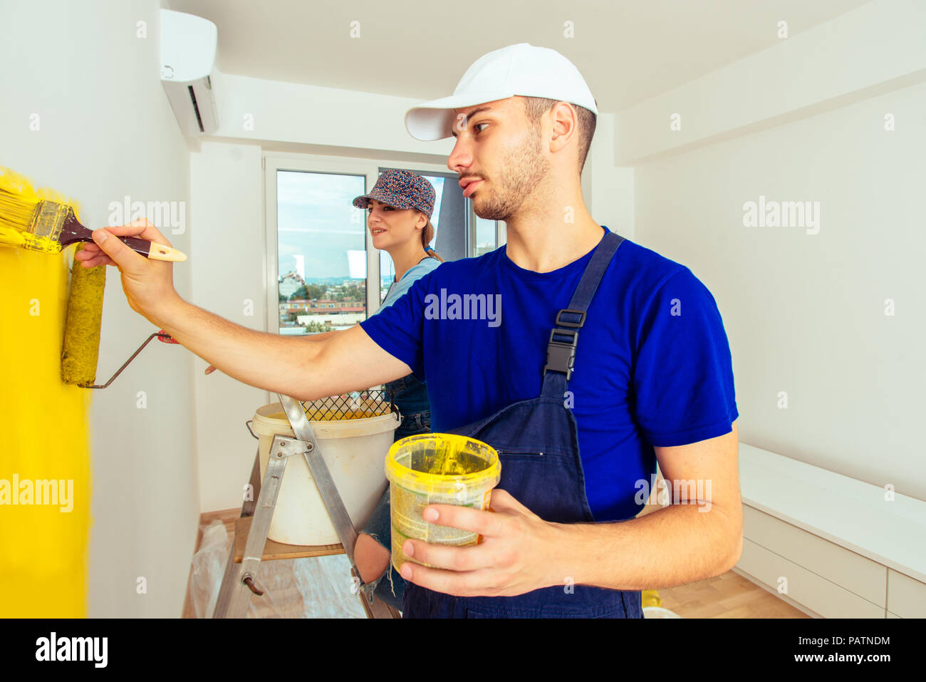 Cheerful couple renovate their new home with yellow color Stock Photo - Alamy