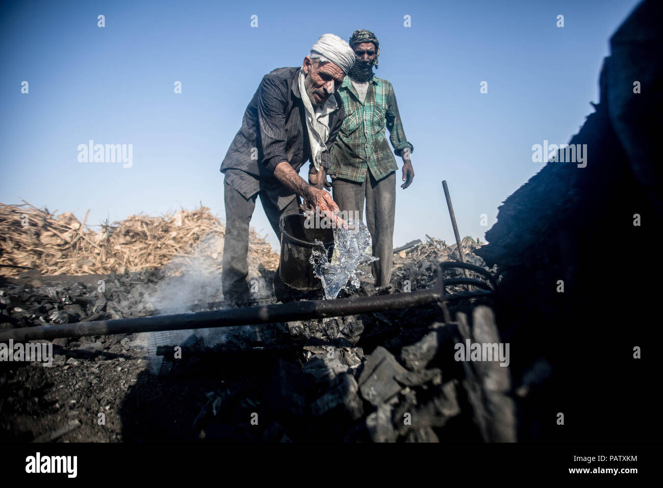 Palestinian worker seen pouring water on burning coal. Charcoal ...
