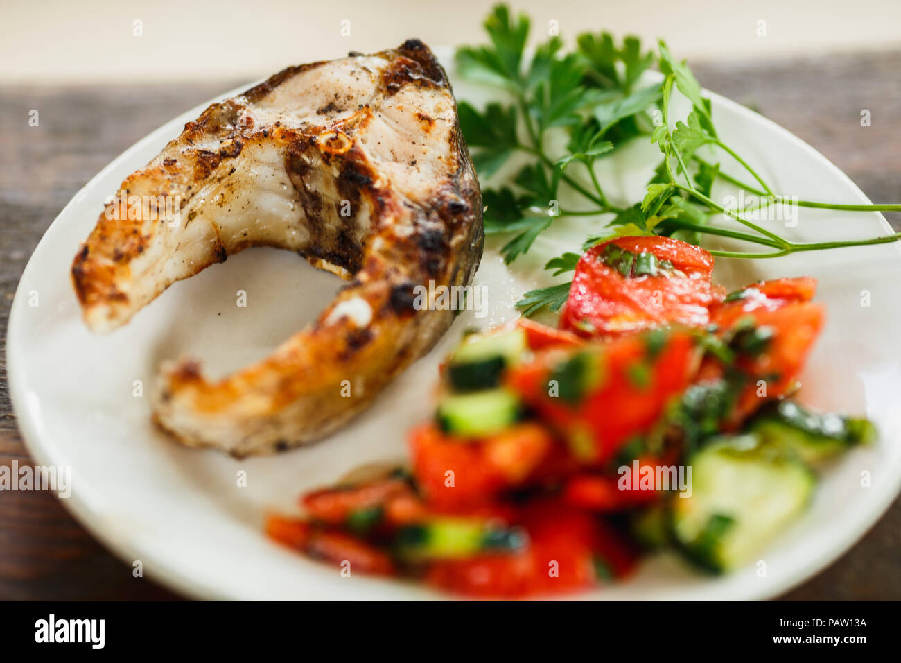 grilled piece of fish with vegetable salad on white plate, healthy ...
