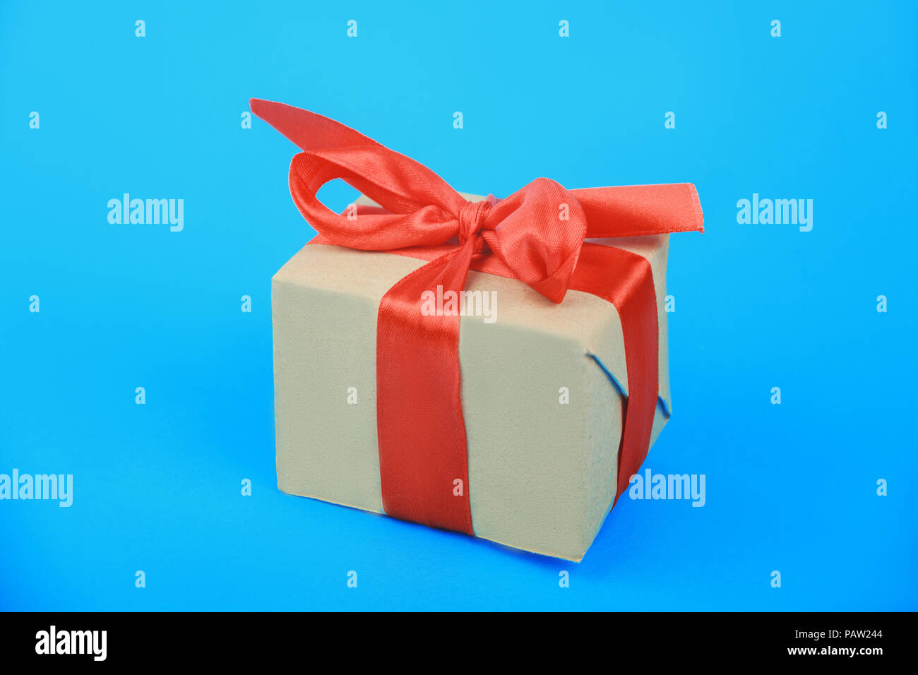 one present gift wrapped with red ribbon close up on blue background ...