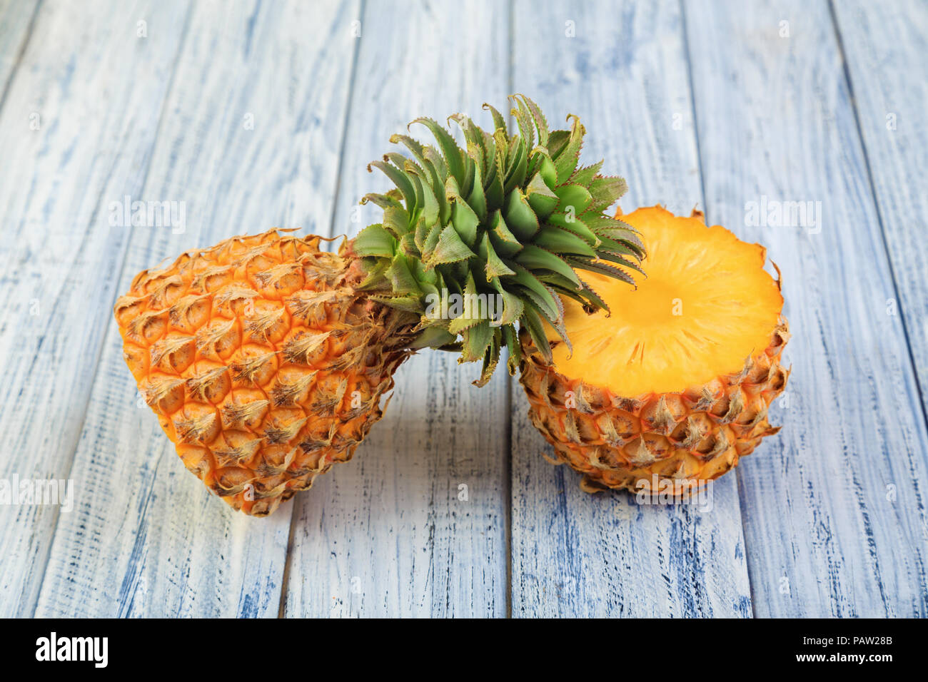 two halves of pineapple, cuteed ripe pineapple on light wooden ...
