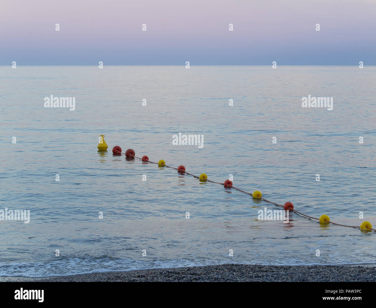 line of colorful plastic buoys delimit an area from a pebbles beach to ...