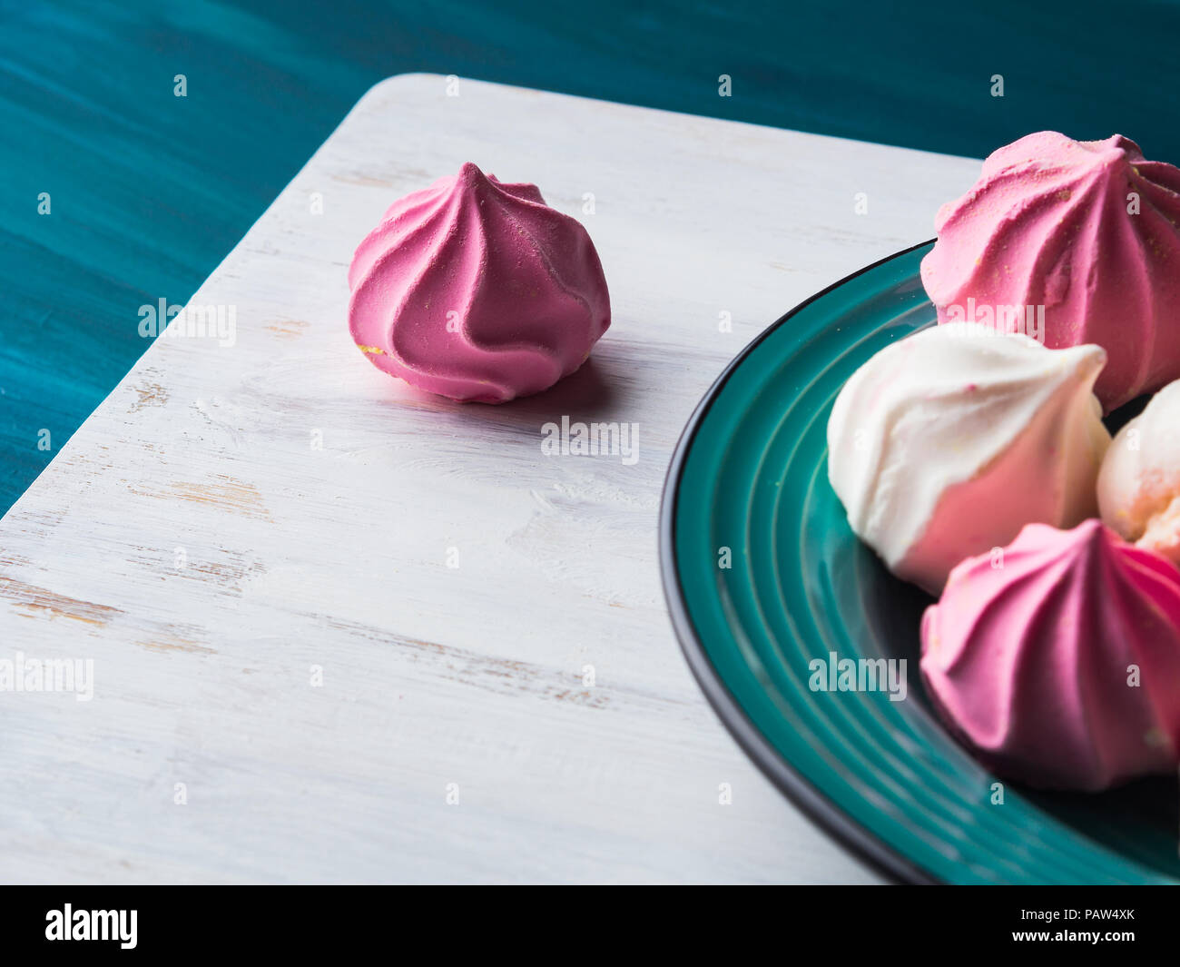 Pastel color pink and white meringue on green background Stock Photo ...
