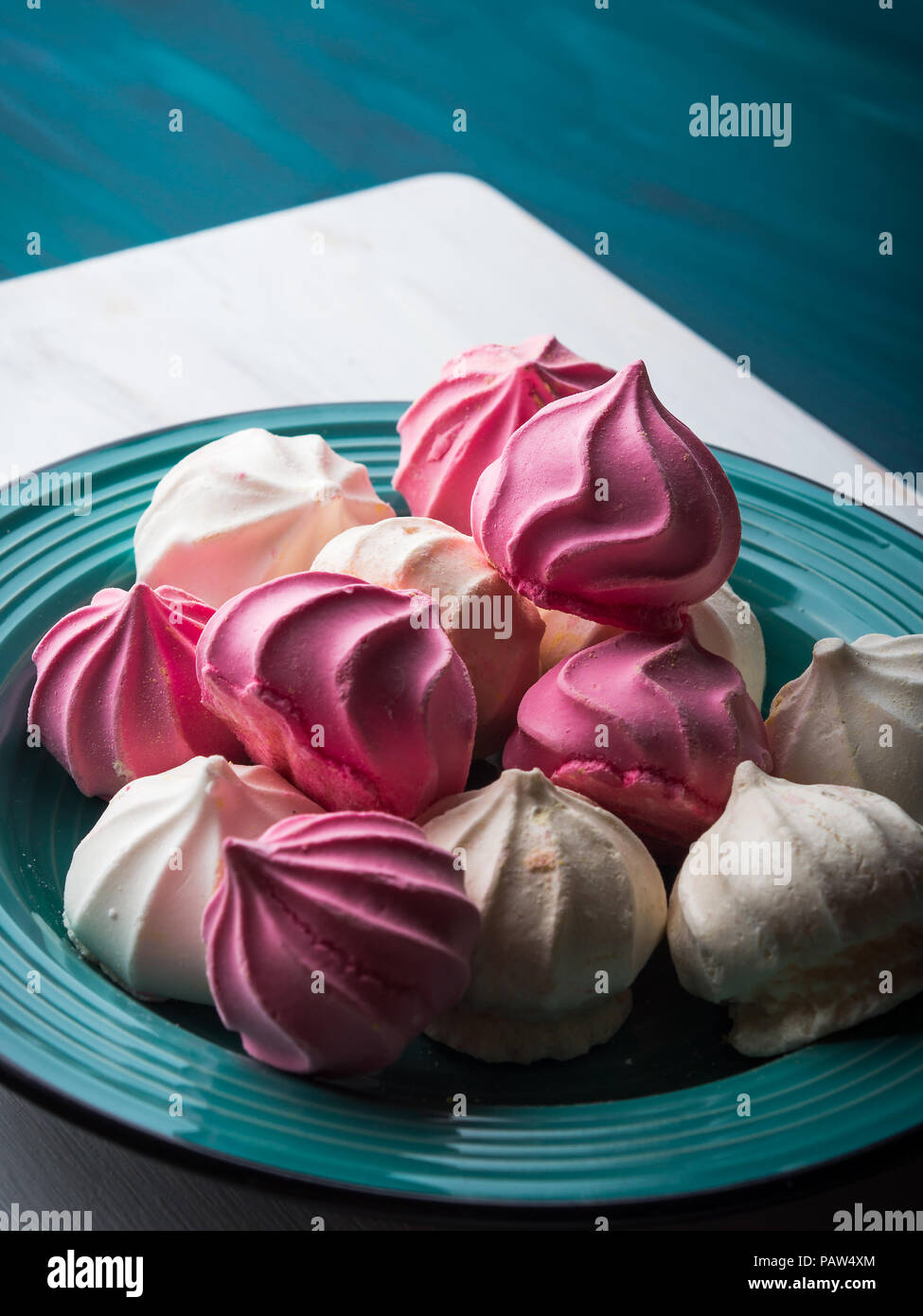 Pastel color pink and white meringue on green background Stock Photo ...