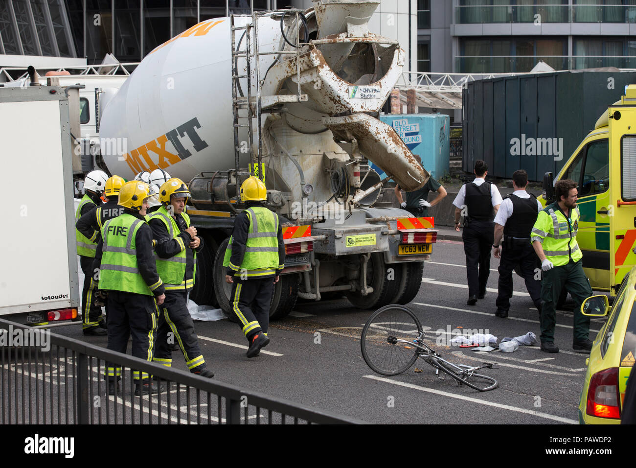 A paramedic looks down at the remains of a cyclists damaged bycycle ...