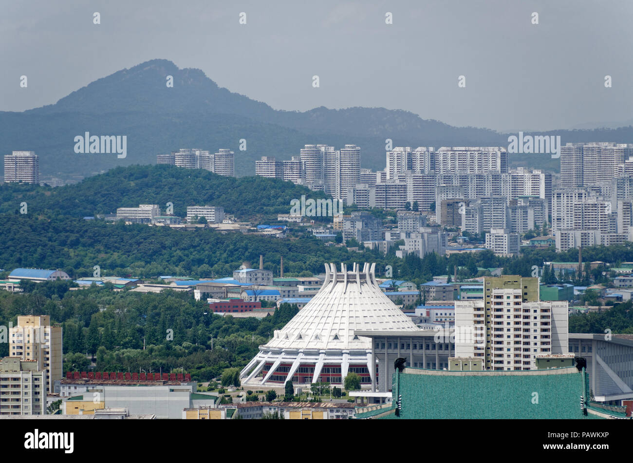 Pyongyang Ice Rink against the tower blocks and mountains of Pyongyang ...