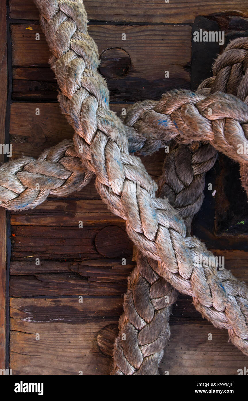 Old braided rope on the wooden deck of a sea boat, cleats, anchor ...