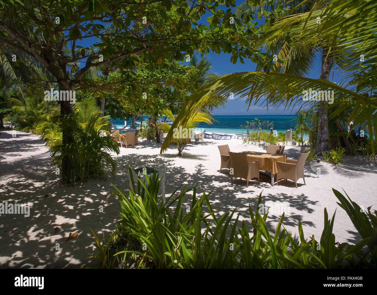 Beachfront tables and chairs for outdoor dining during island vacation ...