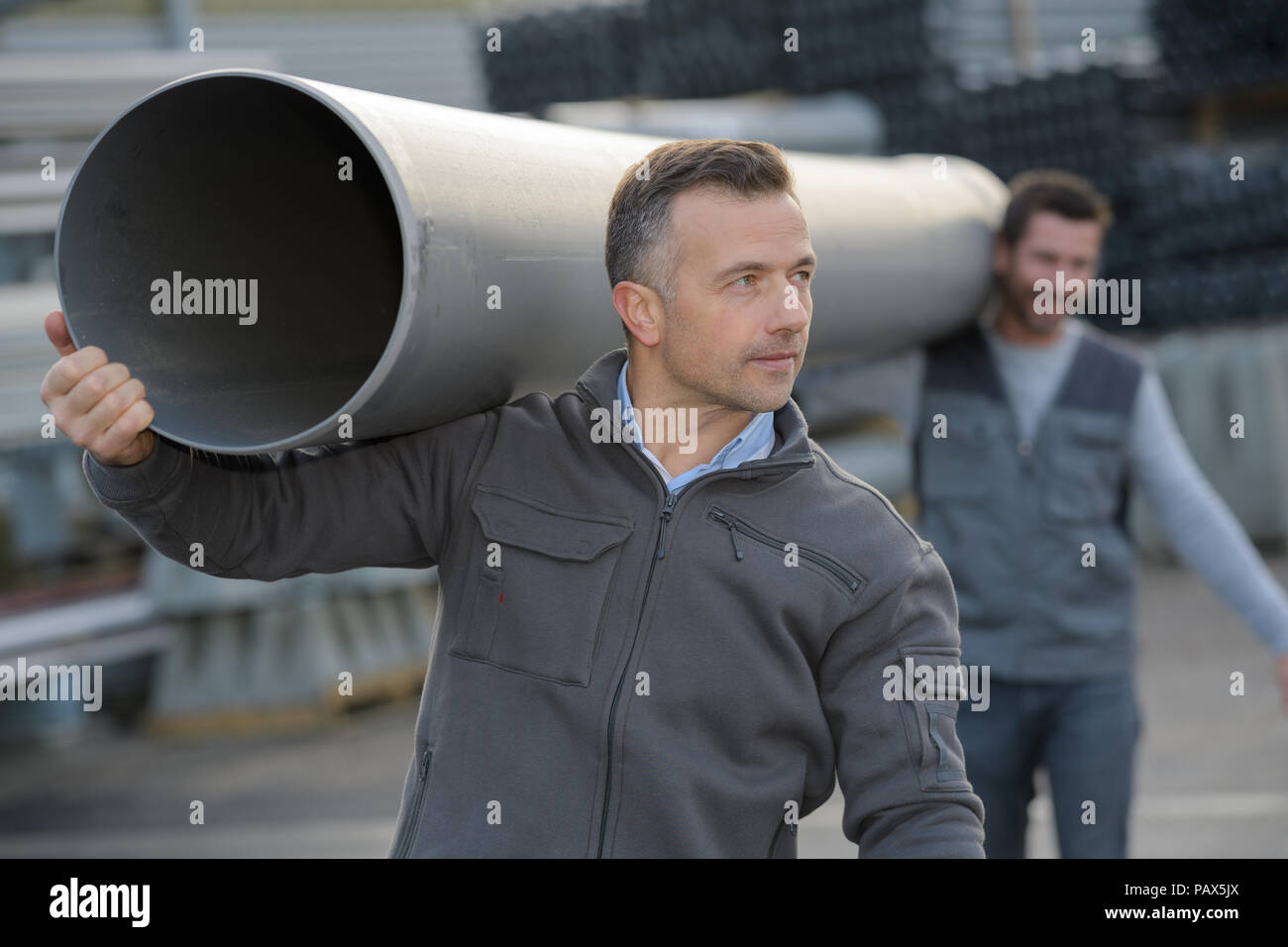 two construction workers on site holding pipe Stock Photo - Alamy