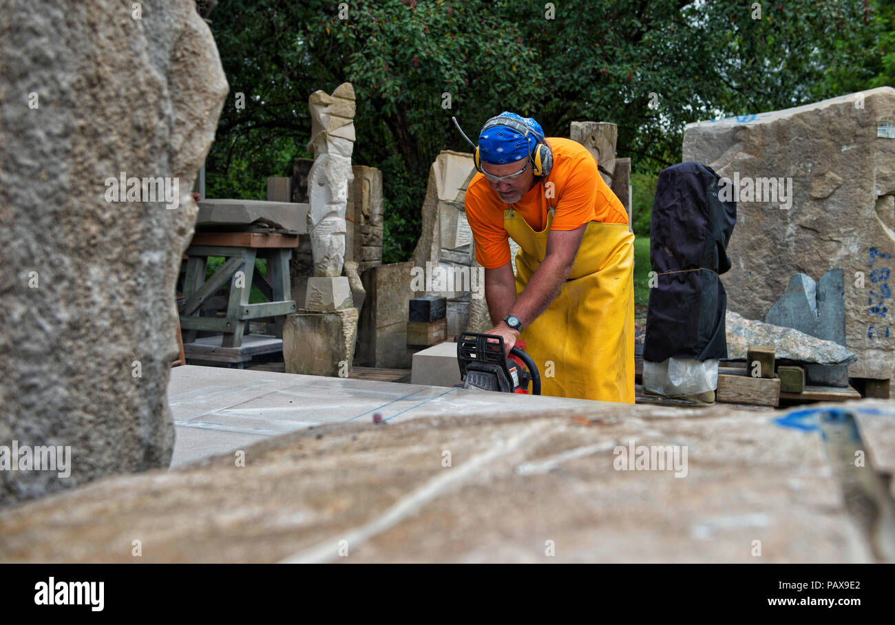 UNITED STATES: July 24, 2018: Sculptor Gary Colson cuts a large slab of ...