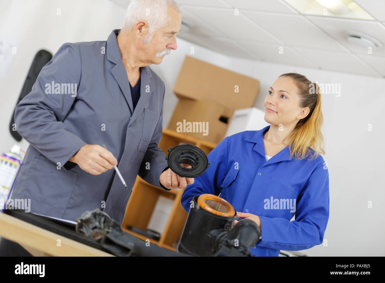 female apprentice mechanic with teacher looking at parts Stock Photo ...