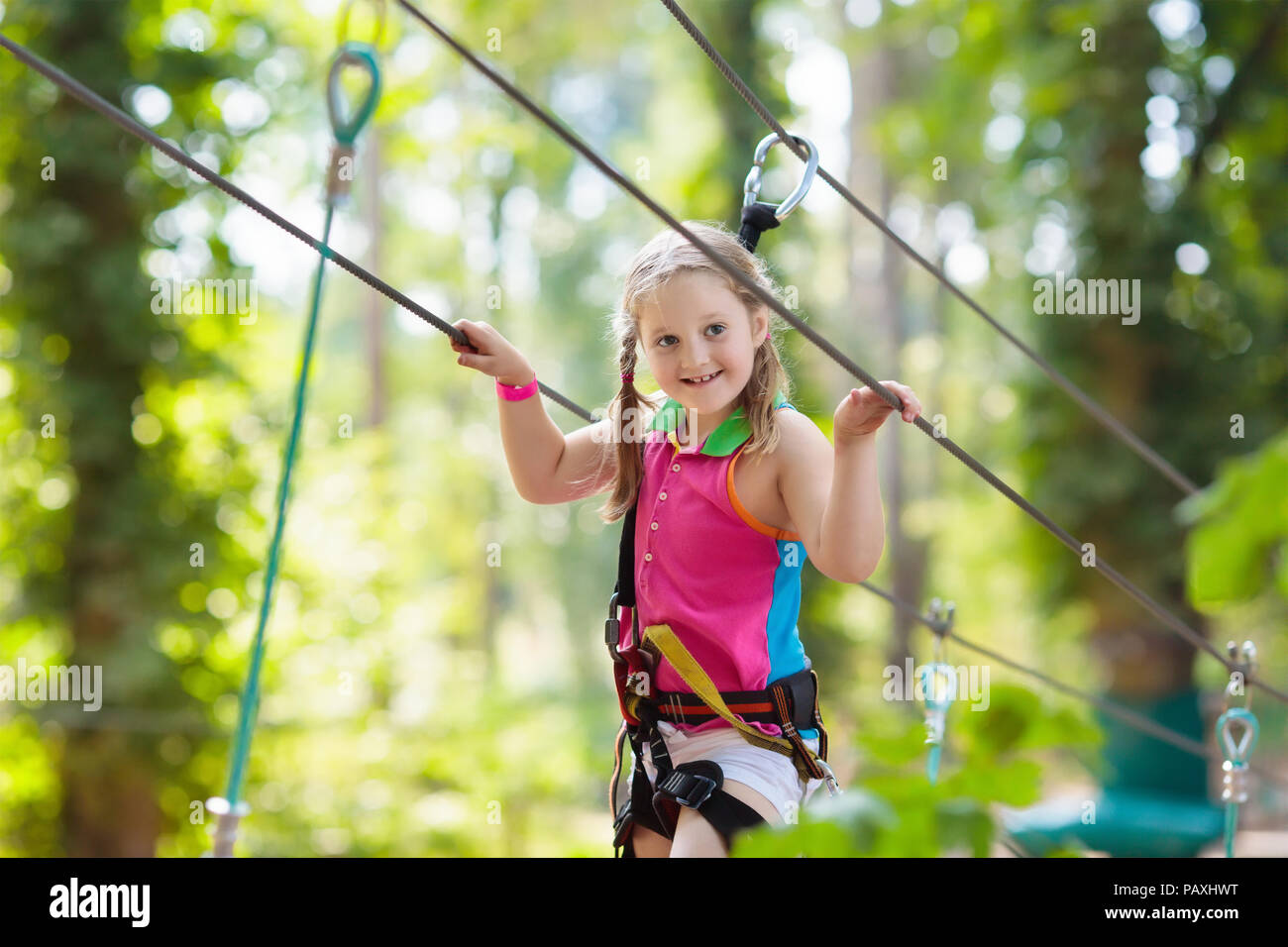 Child in forest adventure park. Kids climb on high rope trail. Agility ...